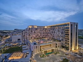 Um hotel moderno com centro de convenções, vários andares e um pátio ajardinado.