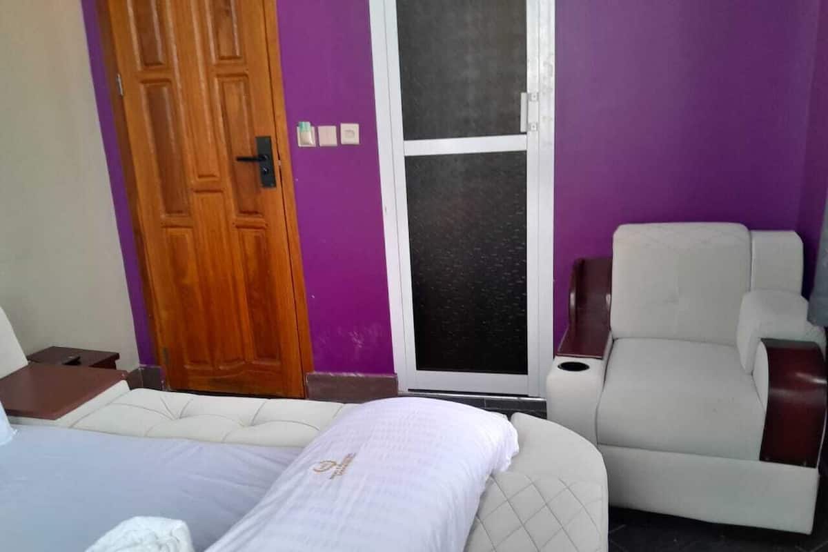 Quarto com cama, cadeira, porta e janela.
