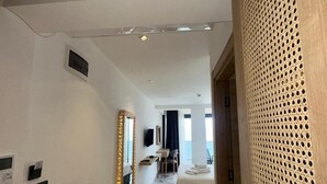 Corredor de hotel com uma cama, uma escrivaninha e um espelho.