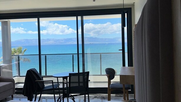 Quarto de hotel com uma janela grande, uma cama, uma cadeira, uma mesa e um abajur.