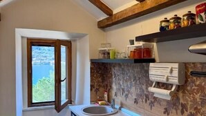 Uma cozinha com janela, vigas de madeira, pia, armários e painel decorativo.