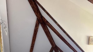 Um quarto com teto inclinado, uma cama com roupa de cama azul, duas mesas de cabeceira e uma mesinha de apoio.