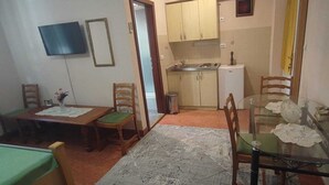 Um espaço compacto com área de refeições, cozinha e uma pequena TV na parede.