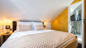 Quarto com cama, luminárias de cabeceira, porta de vidro do chuveiro e vista para o exterior.