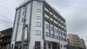 Um edifício com vários andares, fachada branca, diversas varandas e uma série de janelas.