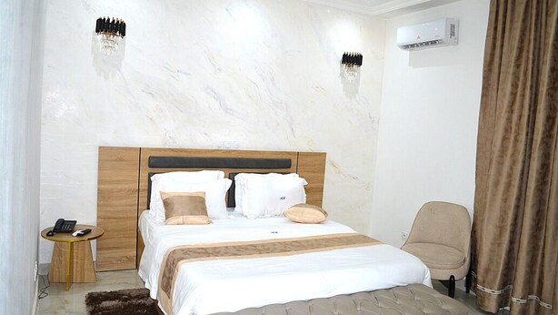 Quarto de hotel com cama, mesa de cabeceira, cadeira e ar condicionado.