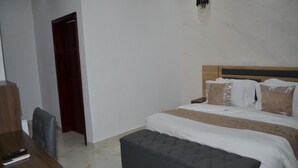 Quarto com cama, mesas de cabeceira, escrivaninha e cadeira.