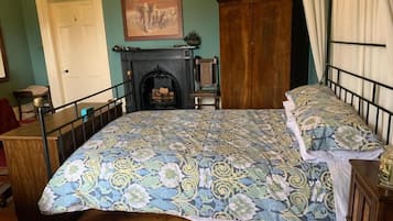 Um quarto com cama, lareira, guarda-roupa de madeira e uma porta.