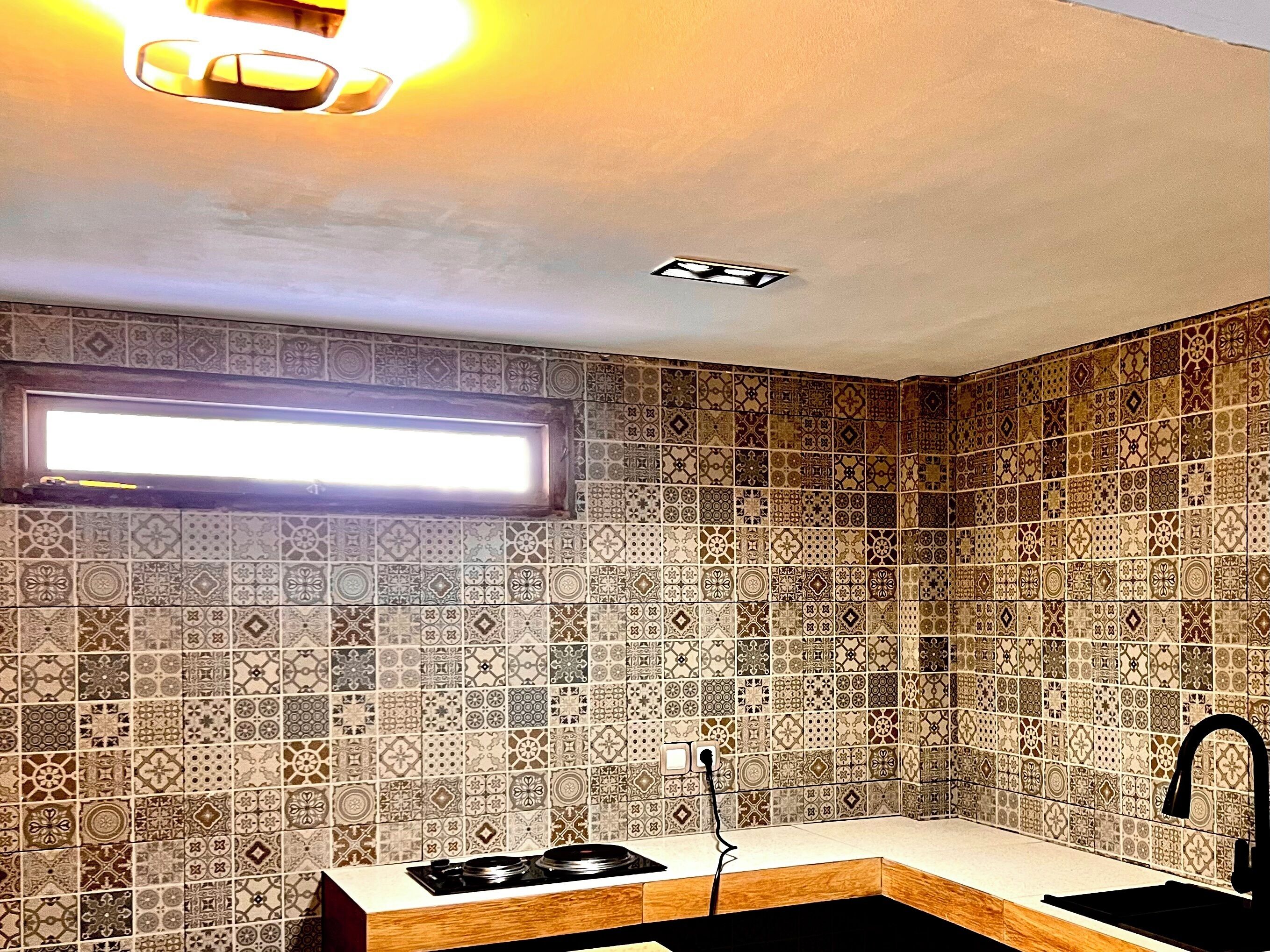 Cozinha moderna com fogão a gás embutido, bancada de madeira e painel de fundo estampado.