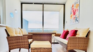 Varanda com mobiliário de vime, uma mesa e uma grande janela com vista.