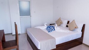 Quarto com cama de madeira, roupa de cama branca, uma cadeira e uma porta com persianas.