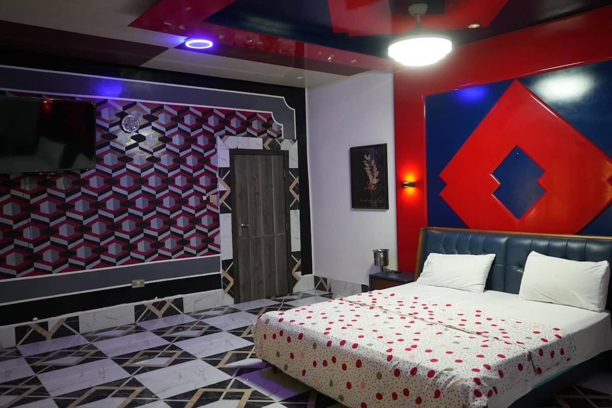Quarto com cama, espelho, parede estampada e design geométrico no chão.