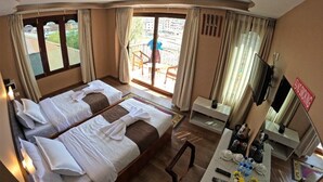 Quarto de hotel com duas camas, uma escrivaninha, televisão e varanda com vista para edifícios.