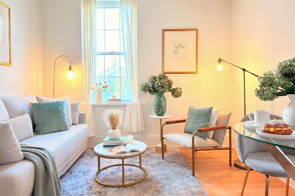 Uma sala de estar aconchegante com sofá, poltrona, mesa de centro e uma mesinha de vidro com um doce.