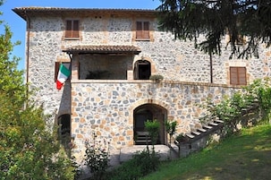 Um edifício de pedra com bandeira, entrada em arco e escadaria que leva a uma porta.