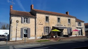 Um edifício de dois andares com café, bar e restaurante no andar térreo.