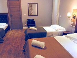 Quarto de hotel com duas camas, uma cadeira, um espelho e um abajur.
