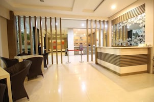 Uma área de recepção de hotel com balcão, espaço de estar e divisória de vidro.