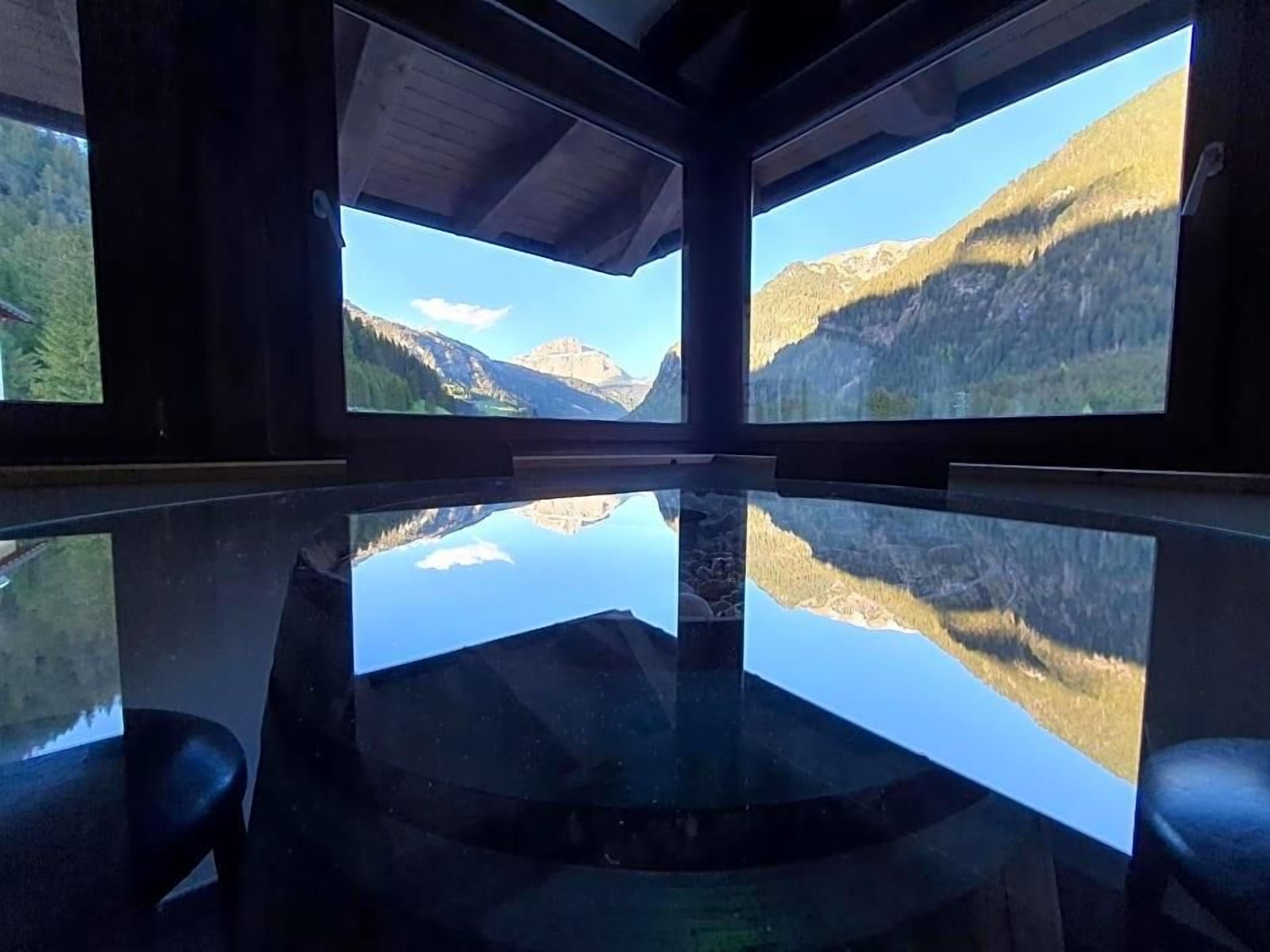 Quarto com piso espelhado, duas janelas e vista para montanhas.