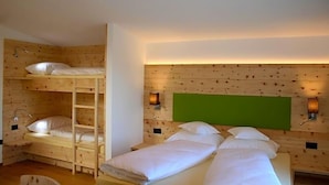 Quarto com beliches, cabeceira verde e luminárias fixadas na parede.
