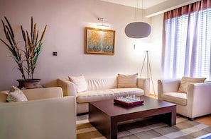 Uma sala de estar com sofá, mesa de centro, quadro e luminária de chão.