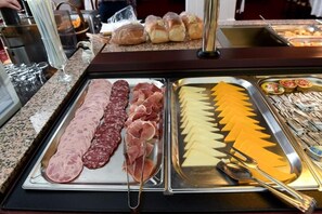 Buffet com fatias de carne, queijos e pão.