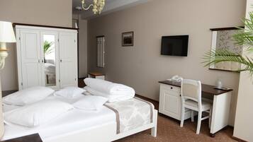 Quarto de hotel com uma cama, uma escrivaninha, uma cadeira, uma televisão e uma planta.