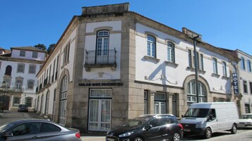 Um edifício com a placa do hotel 'Solar dos Pachecos', apresentando uma fachada tradicional com varanda e grandes janelas.