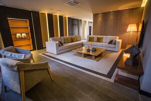 Uma sala de estar moderna com um sofá de canto, uma mesa de centro e um espaço de estar com cadeiras.