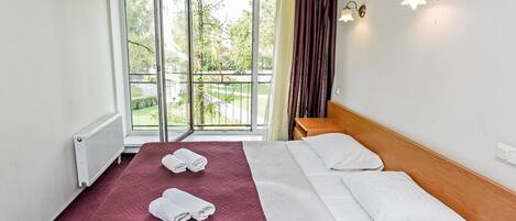 Quarto de hotel com cama, janela com vista para o exterior e mesa de cabeceira.