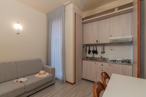 Um espaço compacto com sofá, mesa de jantar e cozinha compacta.
