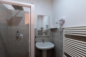 Casa de banho com lavatório, espelho, secador de cabelo e porta-toalhas.
