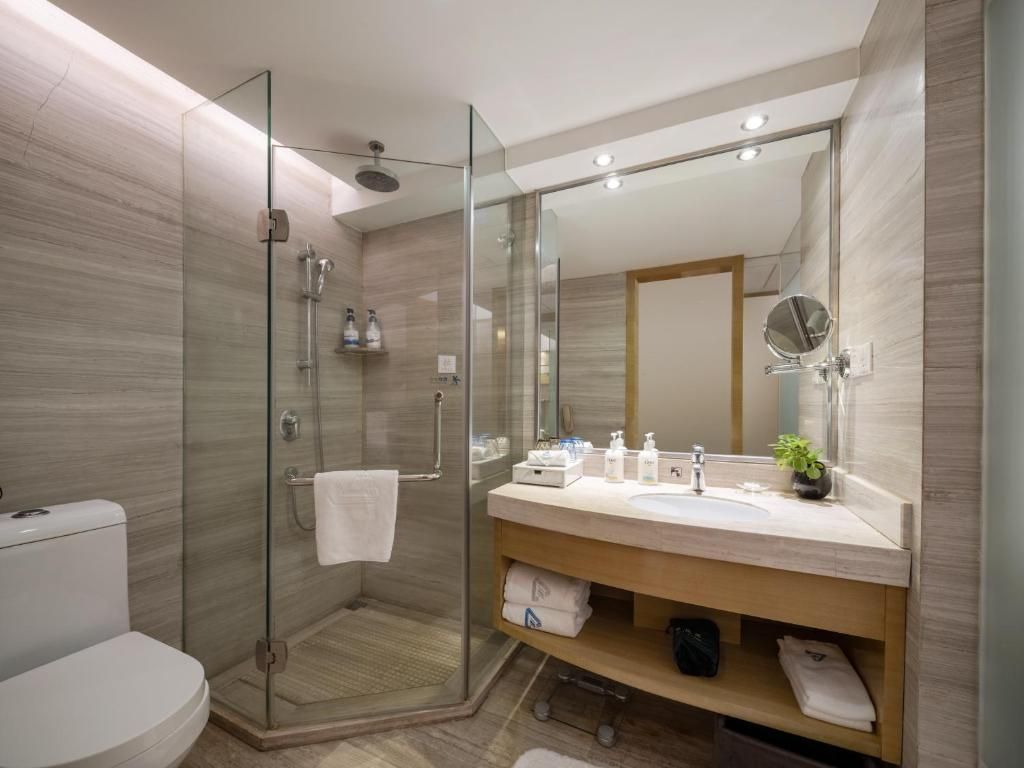 Uma casa de banho moderna com cabine de duche em vidro, um espelho grande e uma toucador com lavatório e espaço de arrumação.