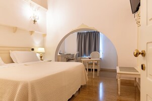 Quarto de hotel com cama, escrivaninha, cadeira e uma pequena mesa.