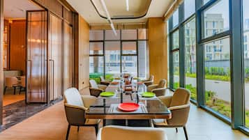 Uma área de refeições moderna com uma mesa comprida, cadeiras e vista para o exterior.