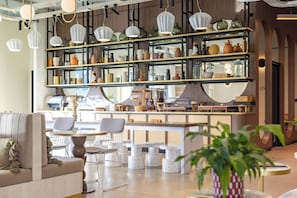 Um interior moderno com área de estar, uma mesa central e prateleiras com diversos objetos.
