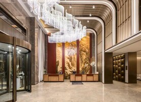 Um lobby moderno com uma mesa de recepção, uma grande instalação de luz abstrata e um mural na parede.