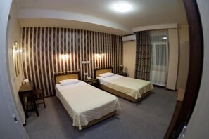 Quarto de hotel com duas camas, uma escrivaninha e uma cadeira.