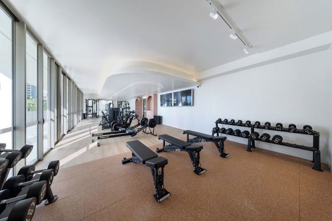 Uma academia com equipamentos de ginástica, bancos e halteres.