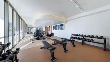 Uma academia com equipamentos de ginástica, bancos e halteres.