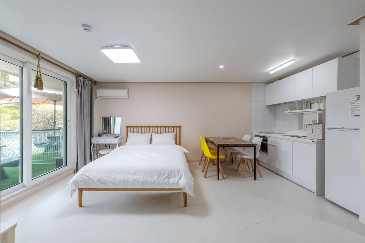 Quarto moderno com cama, mesa de cabeceira e vista para o exterior.