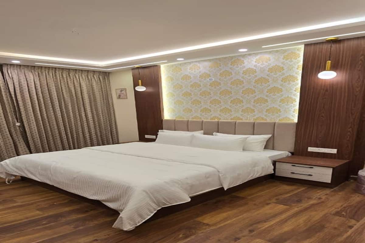 Quarto moderno com uma cama grande, piso de madeira e um design de papel de parede estampado.