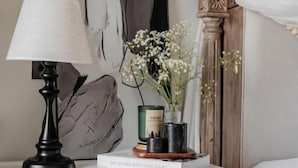 Uma mesa de cabeceira com uma luminária, um livro e um vaso com flores.