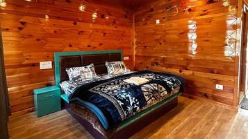 Quarto de cabana de madeira com cama, mesa de cabeceira e ventilador de teto.