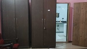 Quarto com guarda-roupa, uma cadeira e porta de acesso a uma casa de banho.