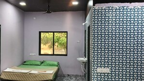 Quarto com cama, janela, pia e cortina estampada.