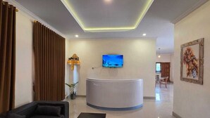 Uma área de recepção moderna com televisão de tela plana, balcão de atendimento e espaço de estar com sofá e mesa.