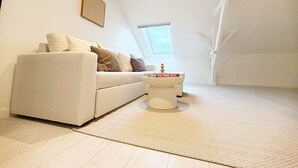 Uma sala de estar moderna com um sofá branco, uma mesa redonda pequena e um claraboia.