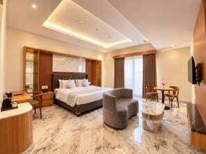 Quarto de hotel moderno com uma cama grande, uma escrivaninha, uma cadeira, uma TV e um espaço de banheiro.