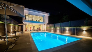 Uma casa moderna com piscina, área de estar externa e interior bem iluminado.